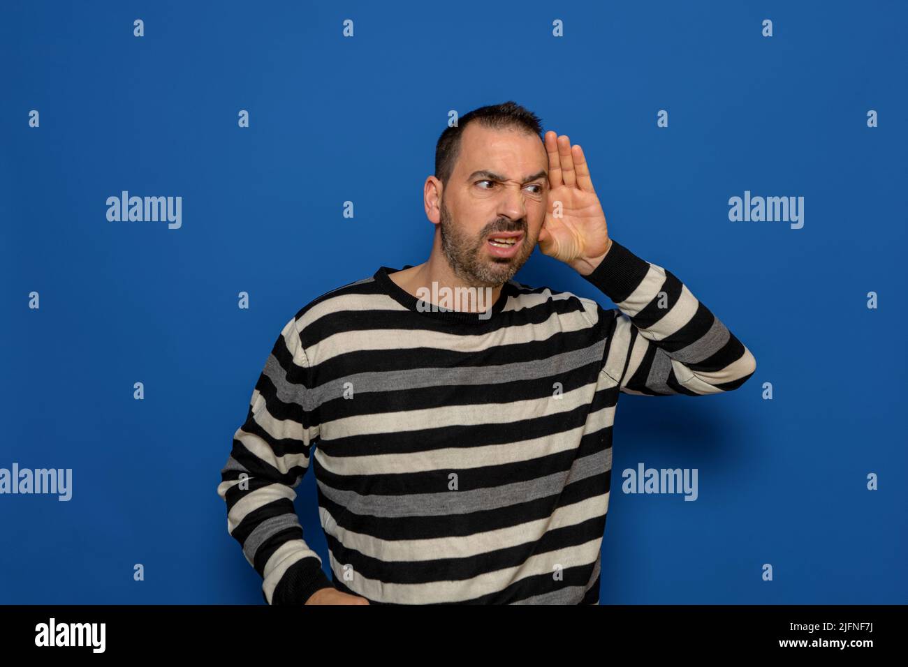Listening man holds his hand near his ear on a blue background ...
