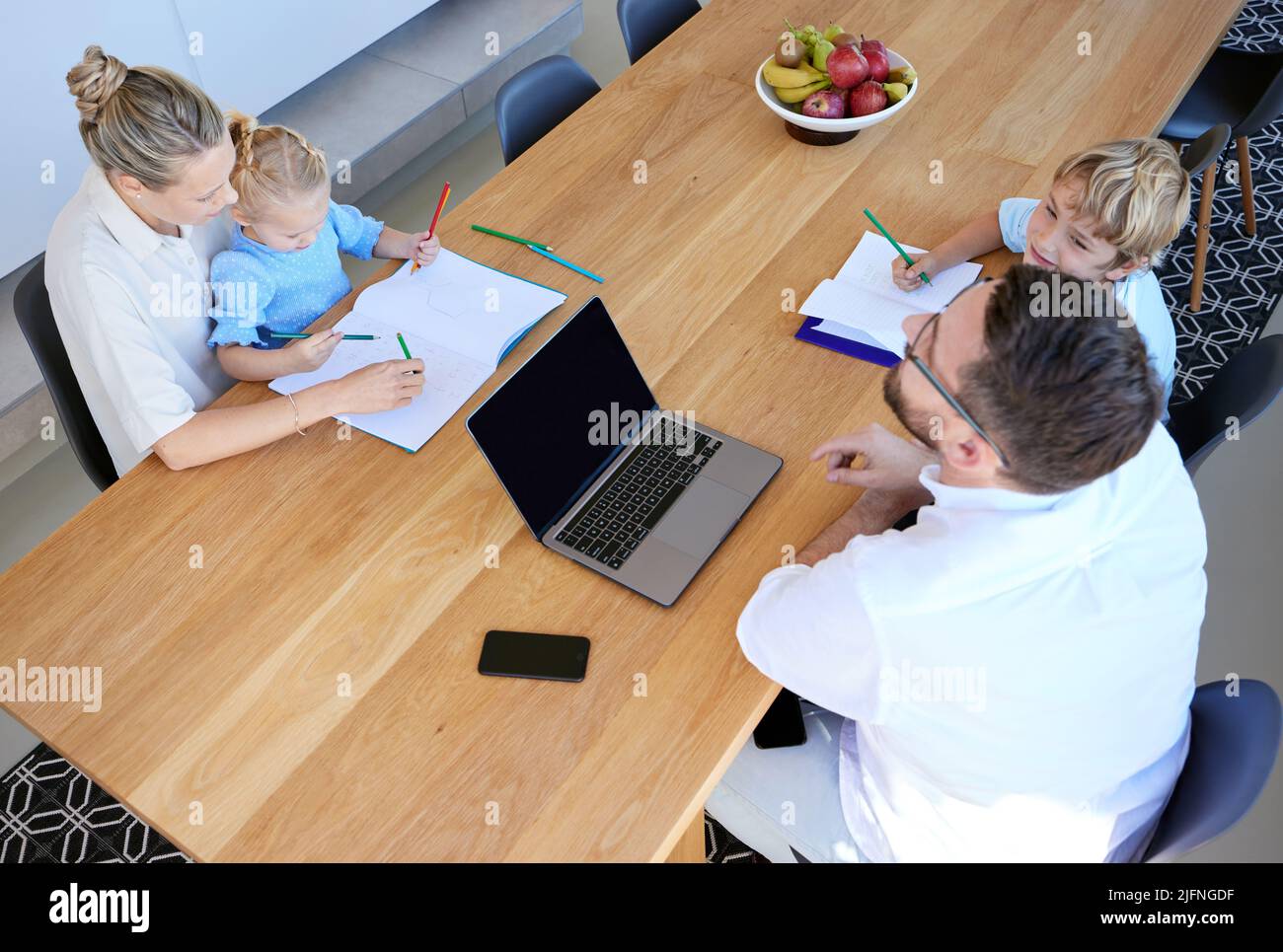 Family working at a table from above, doing homework at home. A young ...