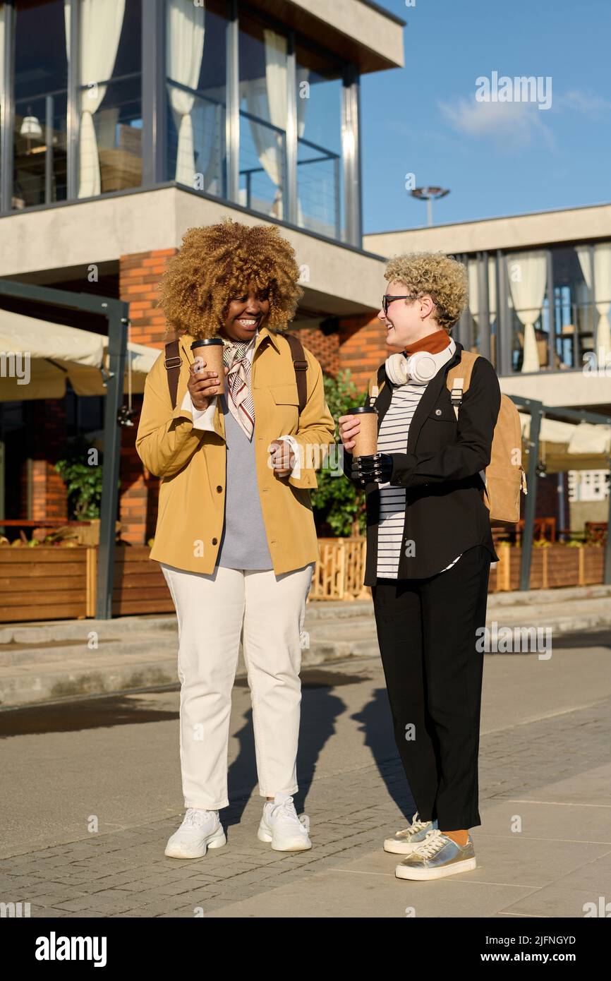 Two friends talking and drinking coffee outdoors during their meeting ...