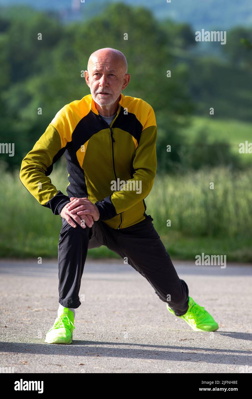 Senior man stretching legs in sportswear outdoor in spring time ...