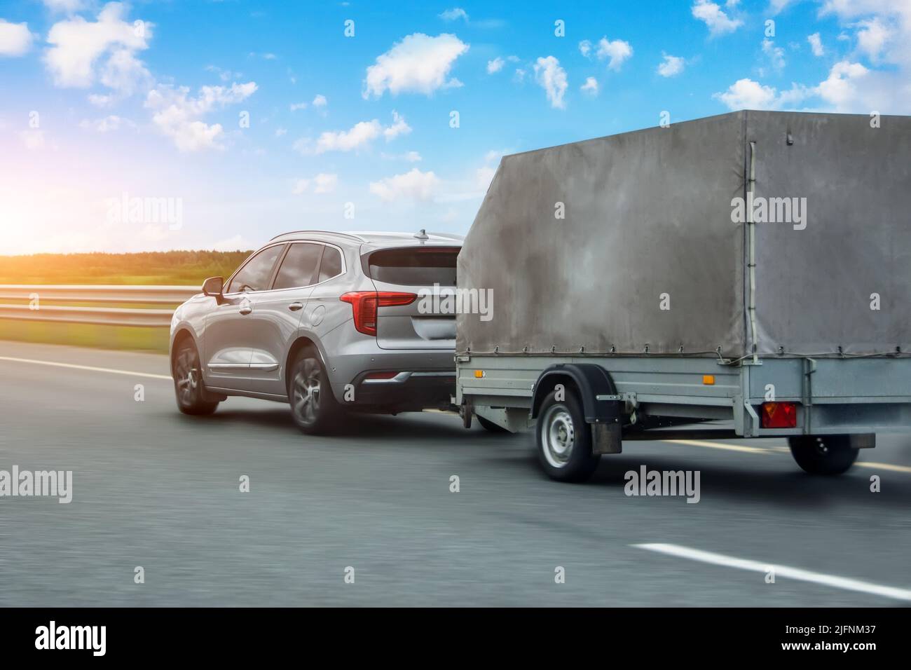 Car with a trailer covered with an awning is driving along the highway ...
