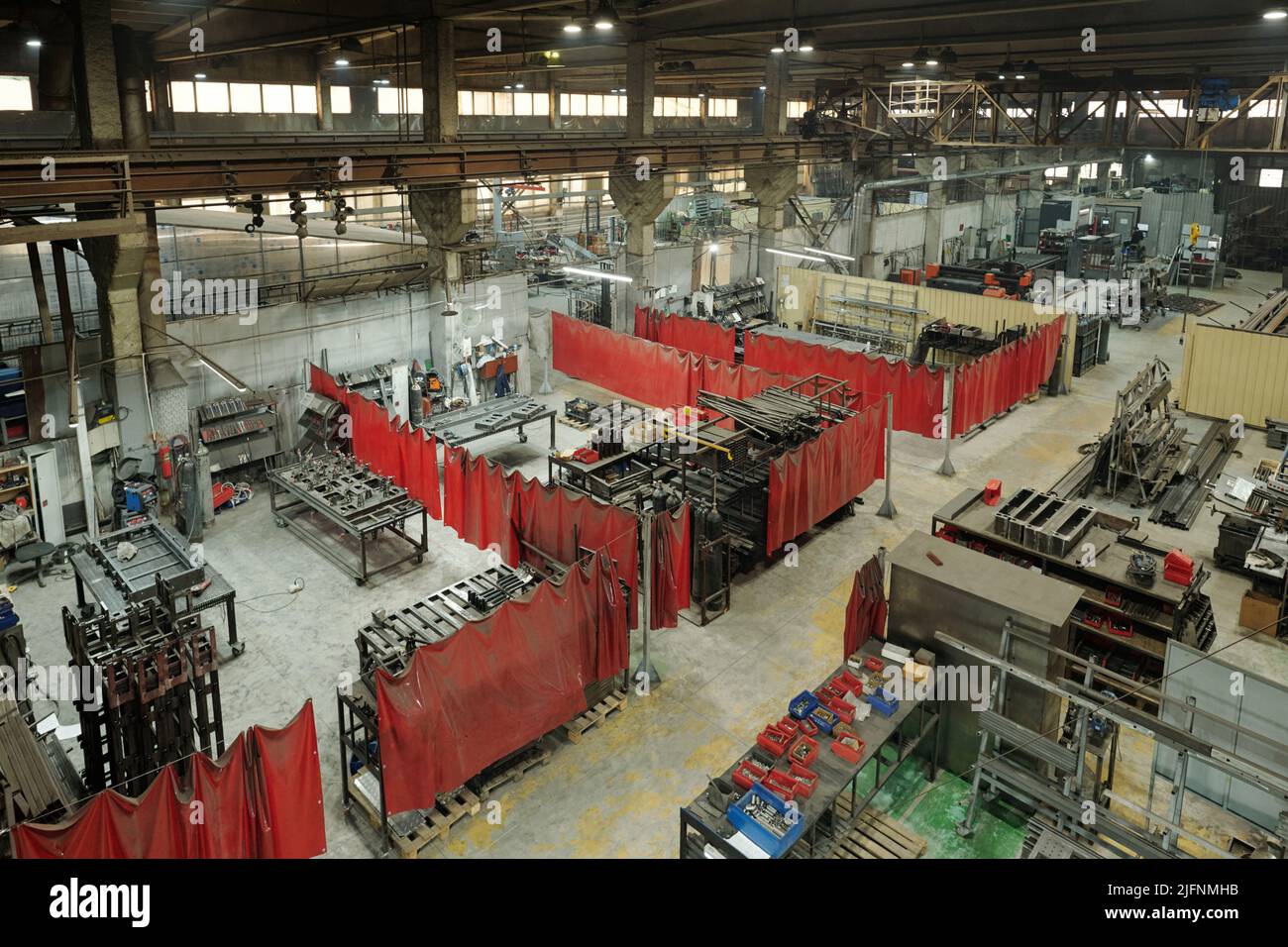 Red curtains dividing several workshops with machines or parts of ...