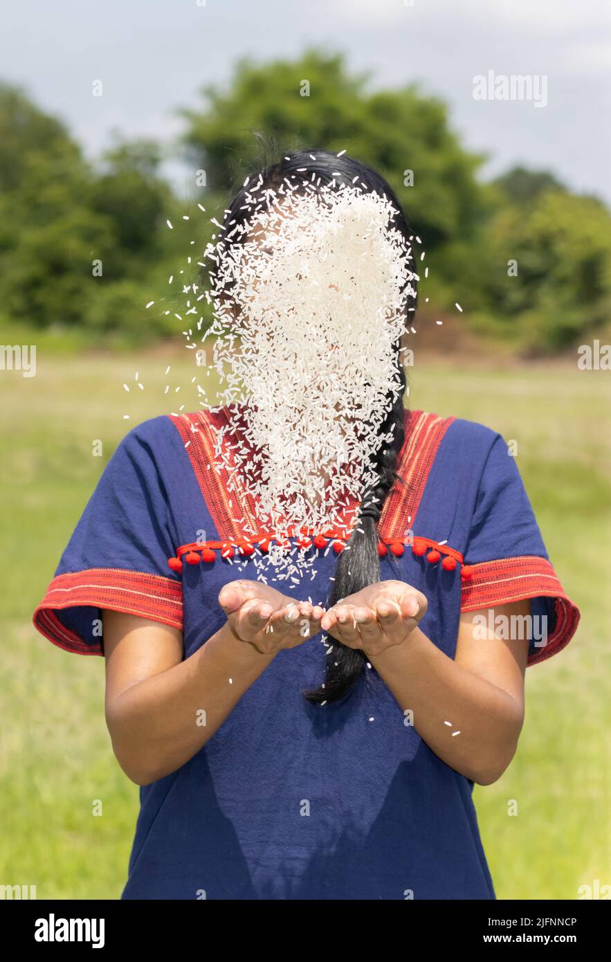 Asian girl in traditional dress stands in a field and throws a handful ...