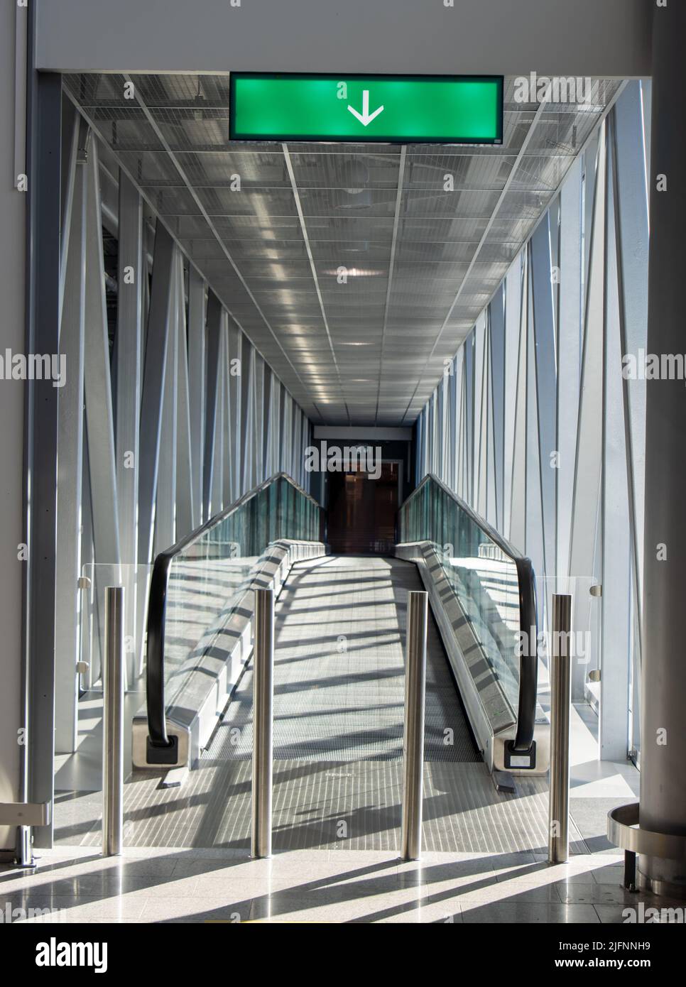 The entrance into an empty corridor with a moving sidewalk lit by the ...