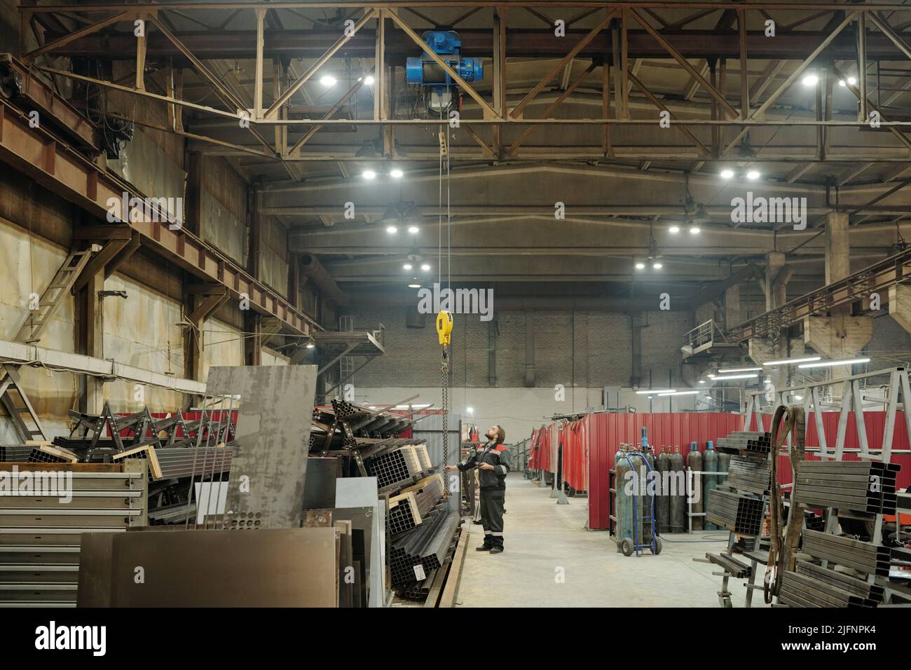 Interior of spacious factory workshop where male engineer adjusting ...