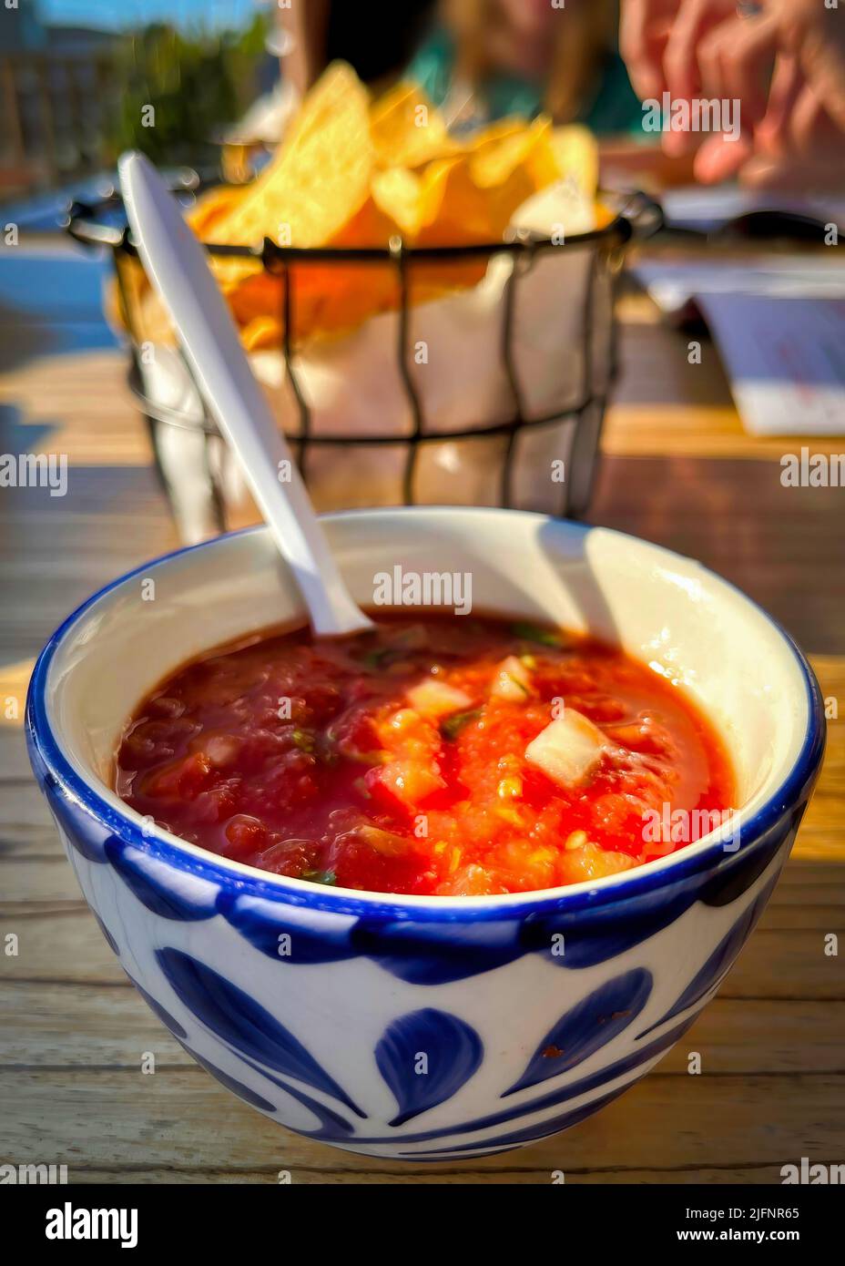 The sun sets on a bowl of salsa, ready to eat, at a table on a patio in ...