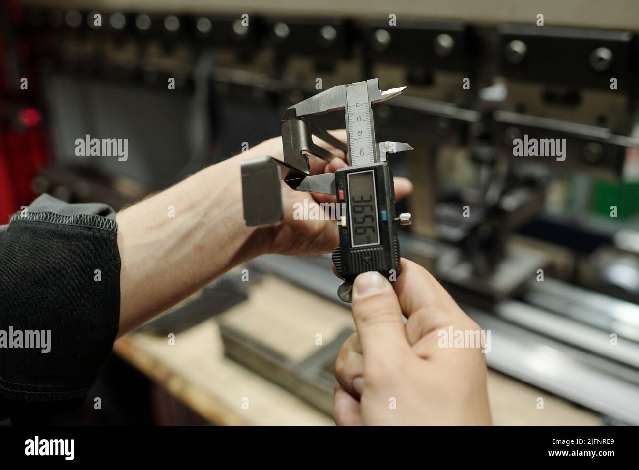 Male engineer taking measures of small stainless steel detail over ...