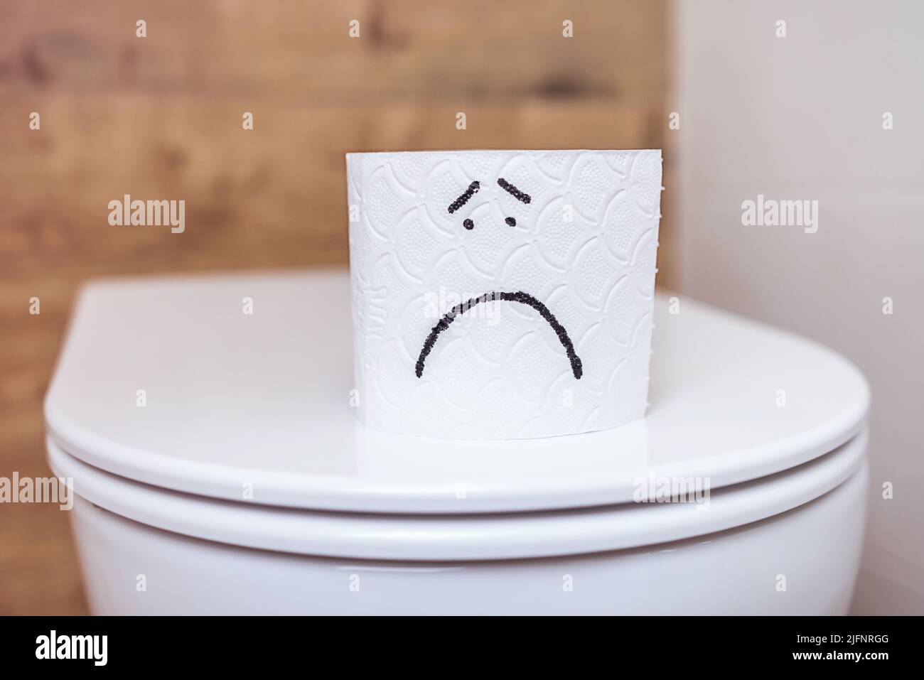 close-up, a roll of toilet paper with a painted sad face stands on the ...