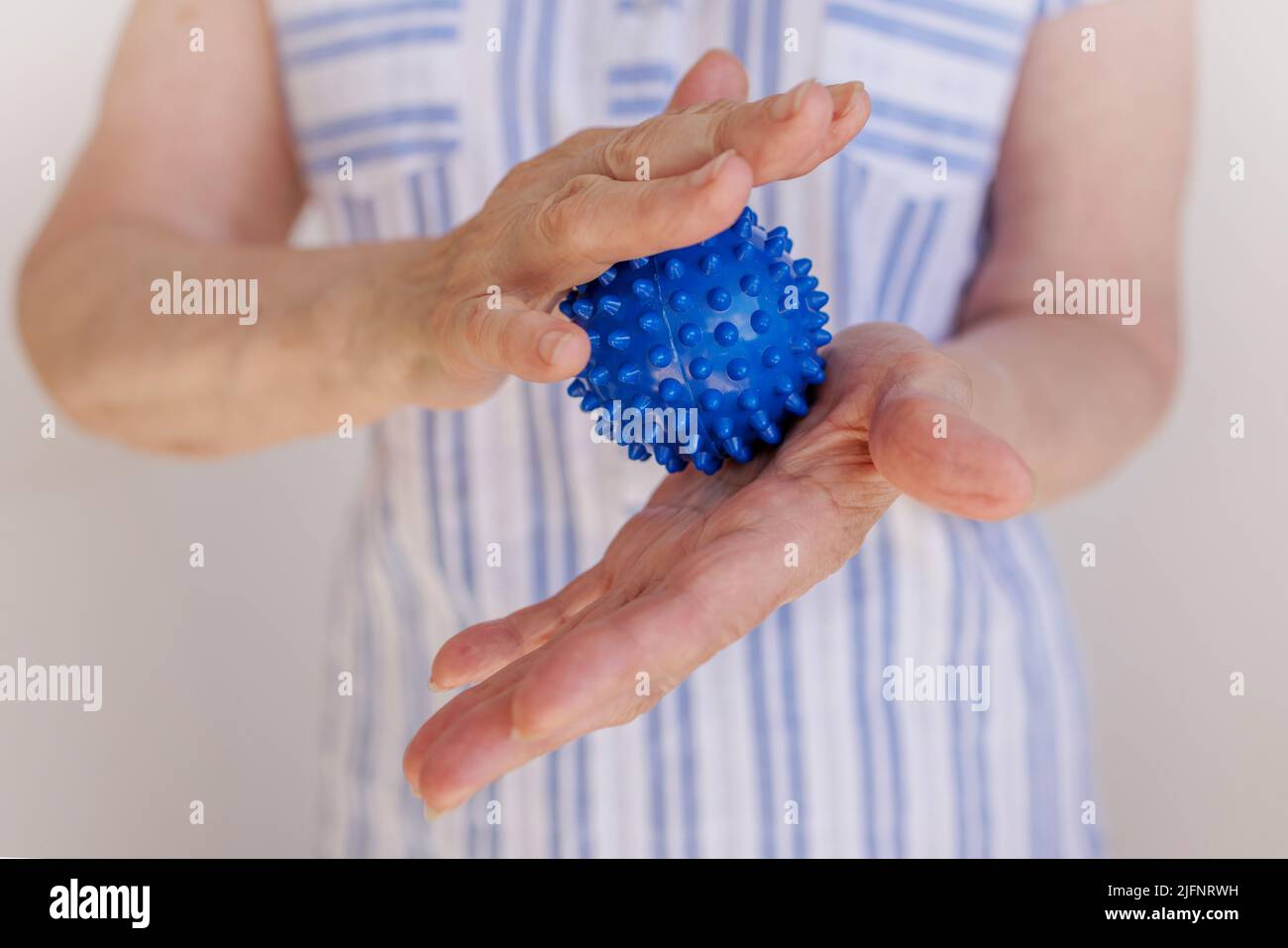 elderly woman squeezes a prickly ball in her hands, self-massage with ...