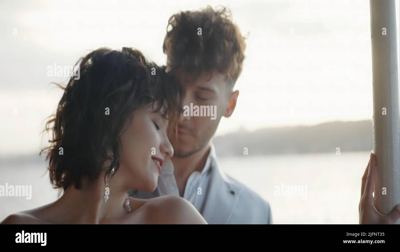 Handsome man and beautiful woman on a date near the river embracing and ...