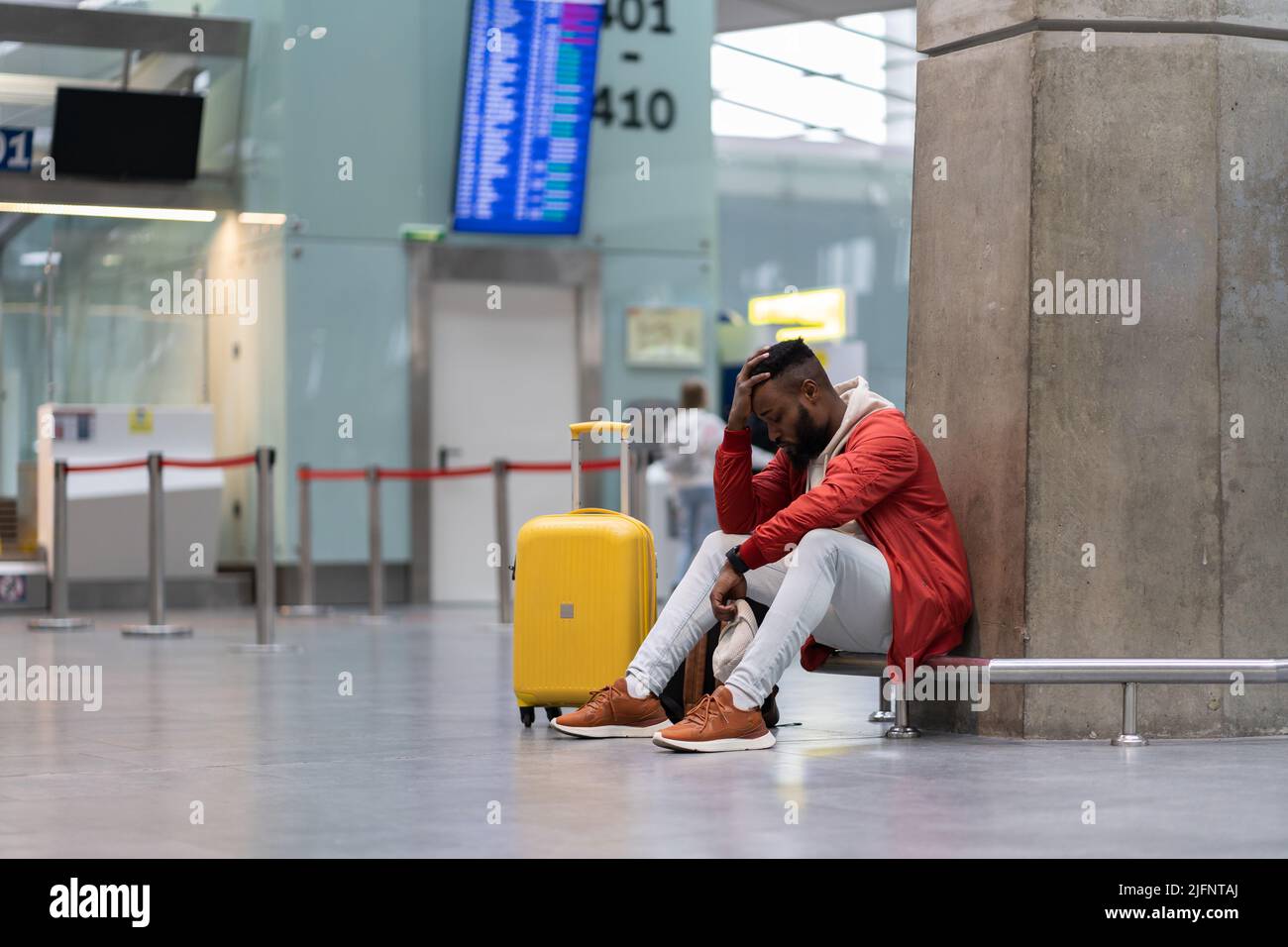Exhausted African man on a long night connection at airport, waiting ...