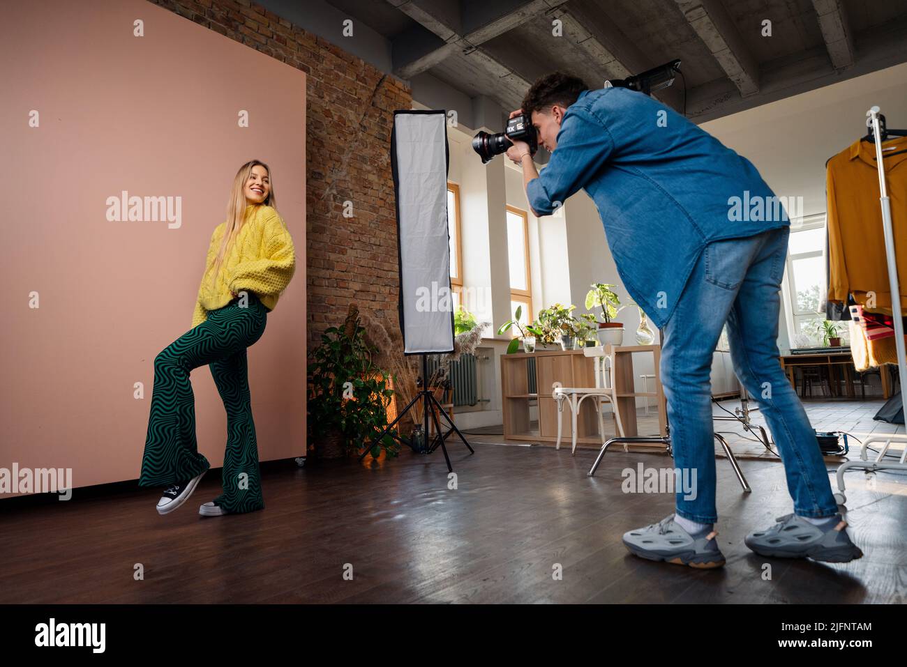 Young photographer taking picures of model, backstage of photoshooting ...