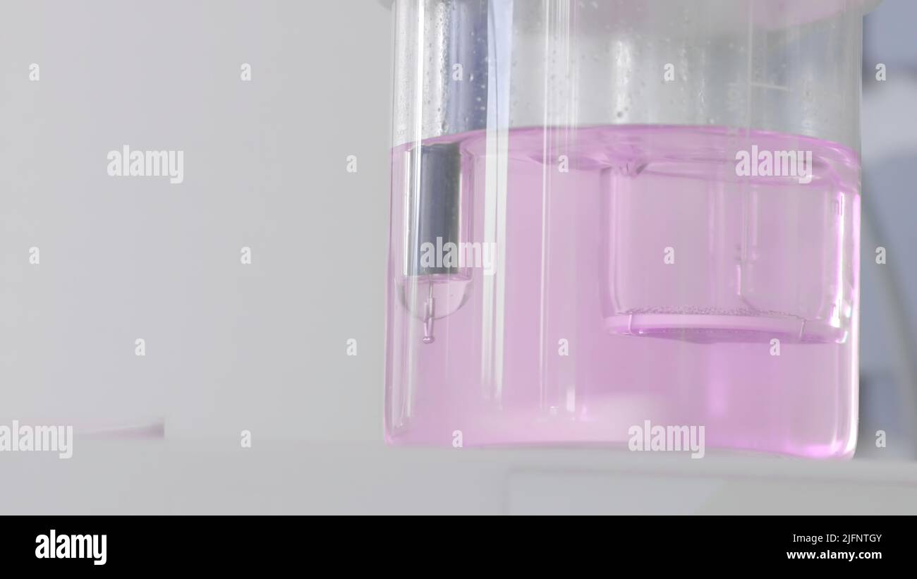 Close-up of pink liquid in transparent container. Action. Bubbling pink ...