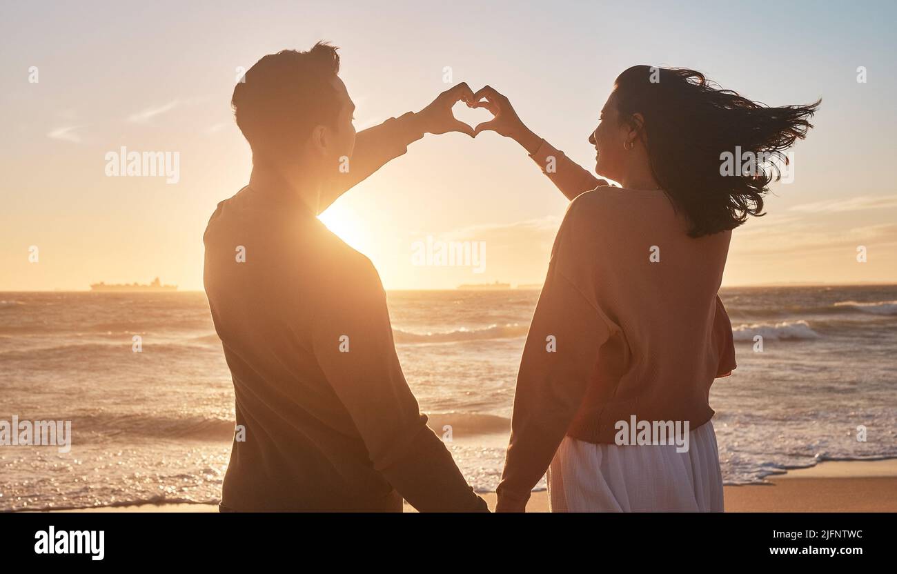 Biracial couple holding their hands together in a heart shape at the ...