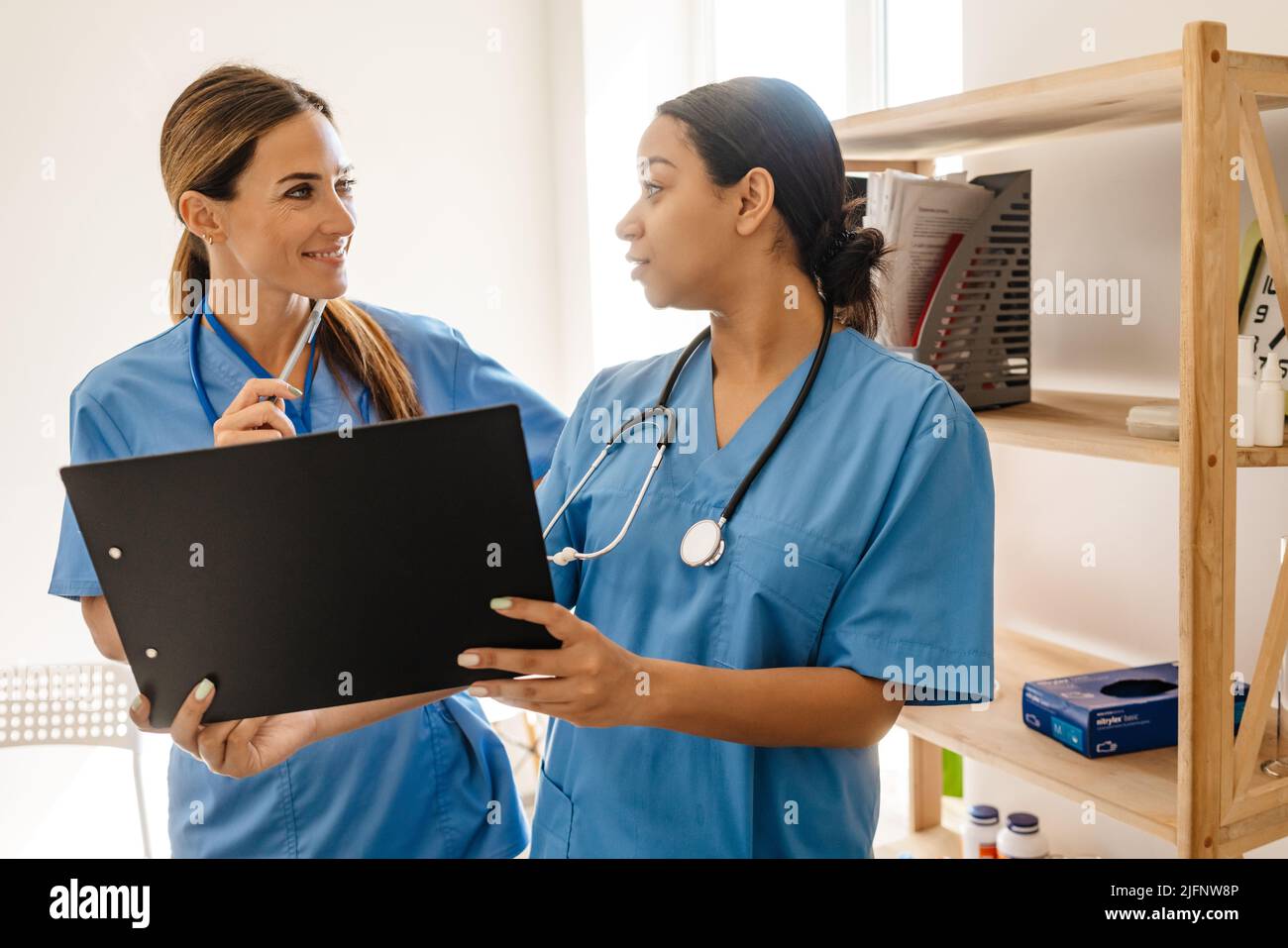 Multiracial women doctors talking while working with papers in office ...
