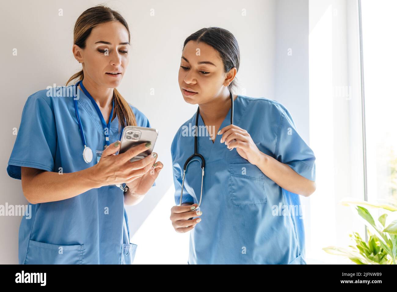 Multiracial women doctors talking and using cellphone while working in ...