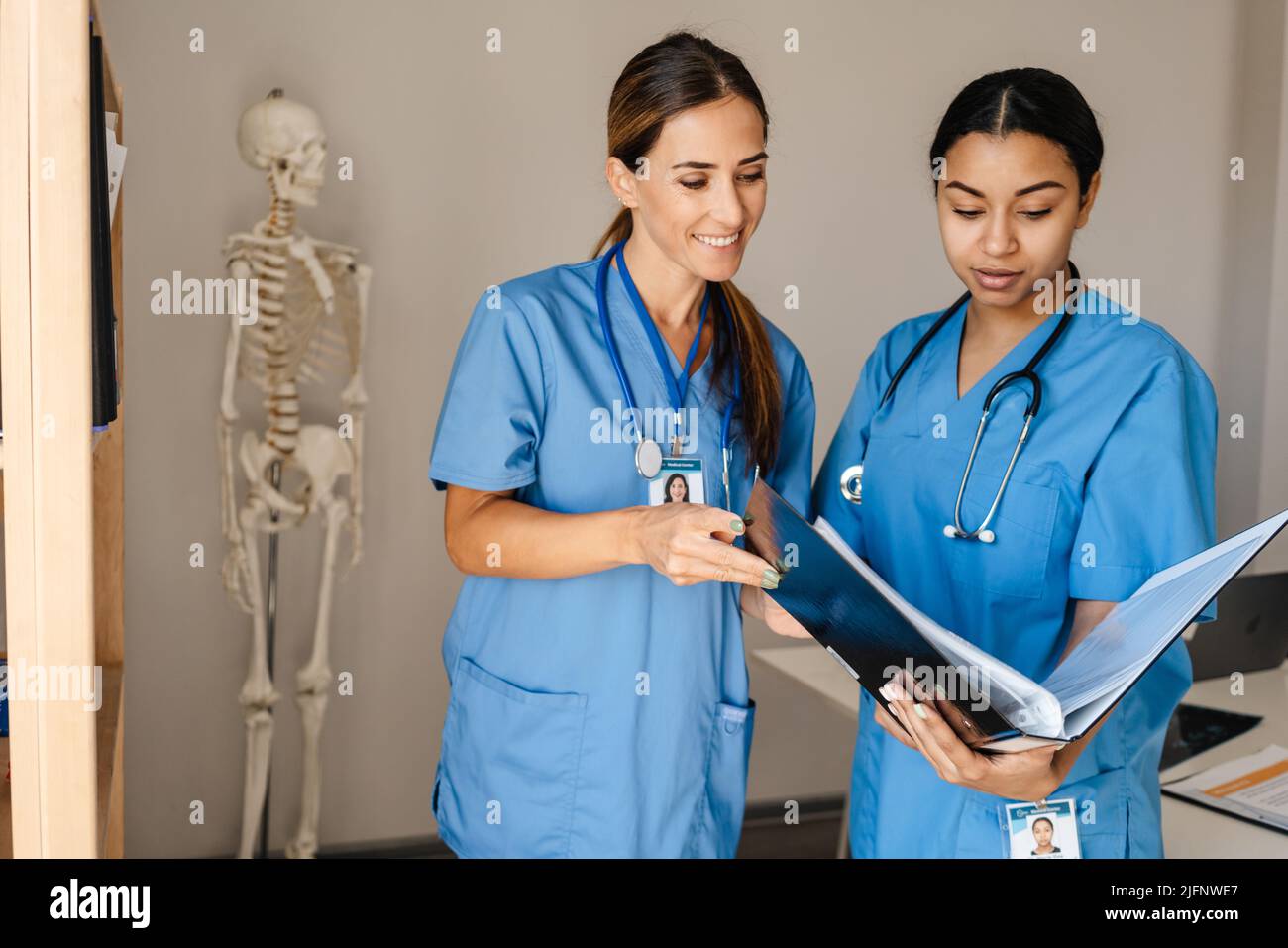 Multiracial women doctors talking while working with papers in office ...