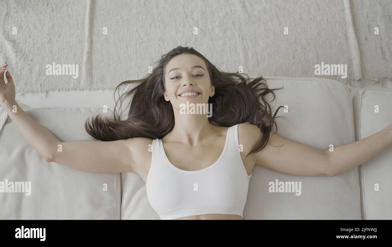 Happy woman falls on bed. Action. Beautiful woman smiling falls happily ...