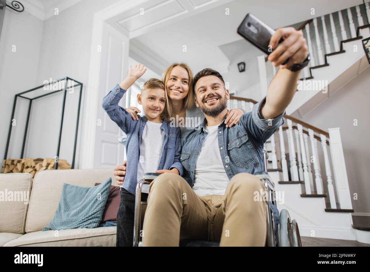 Smiling family standing near father with special needs and looking at ...