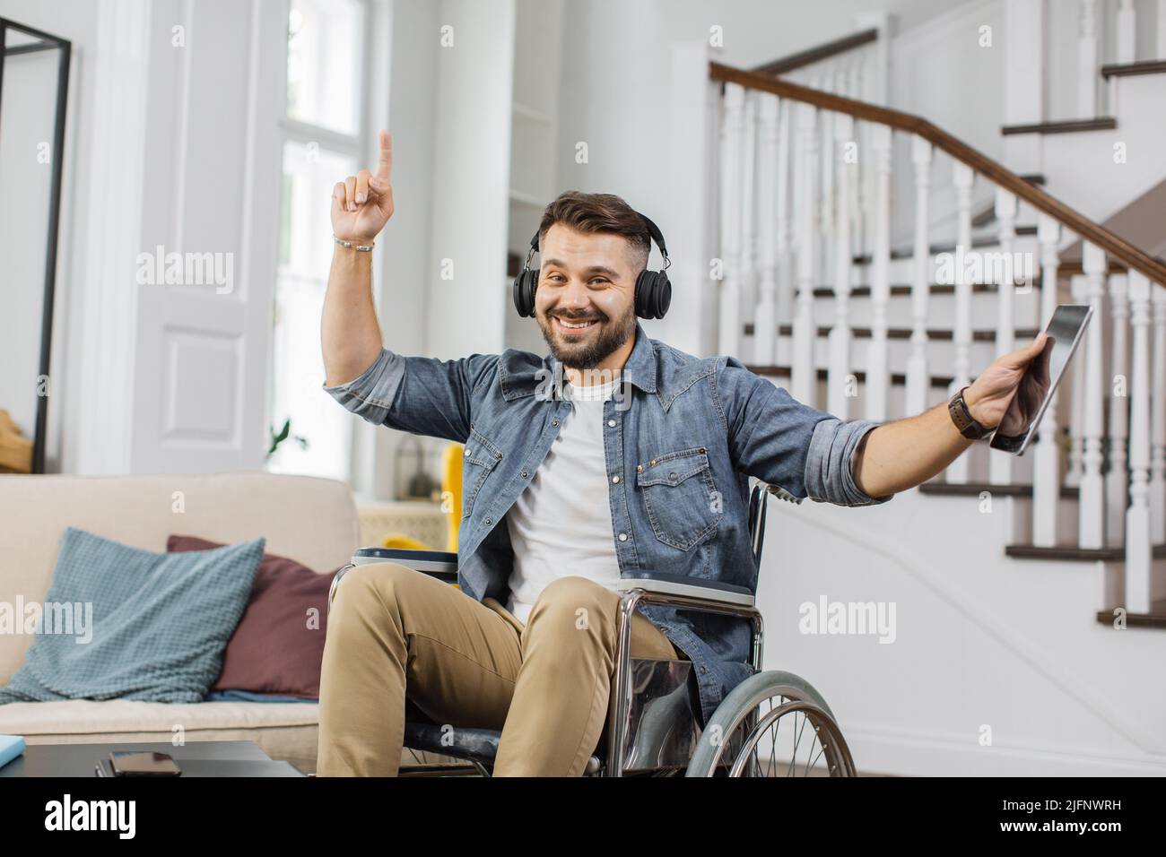 Happy disabled man in headphones holding modern tablet and listening ...