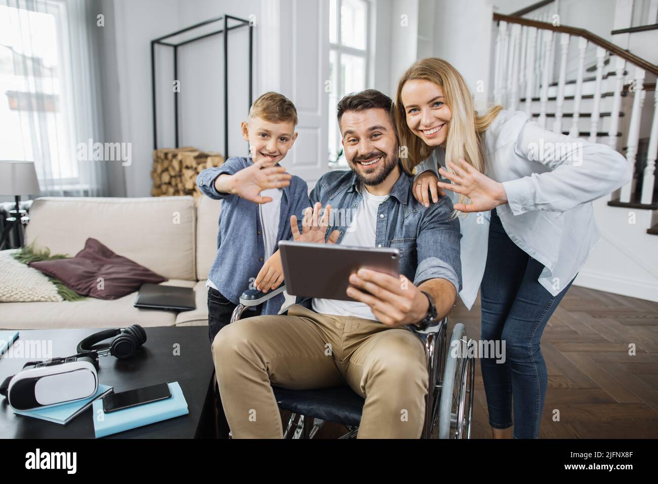 Portrait of disabled husband with blond wife and cute son posing ...