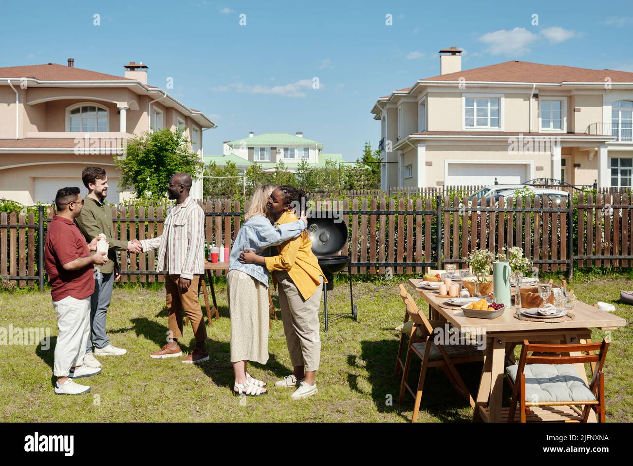 Happy young black man and woman meeting guests by served table prepared ...