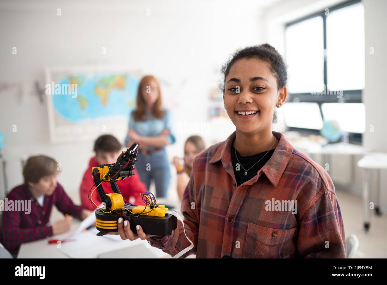 College student holding her robotic toy at robotics classroom at school ...