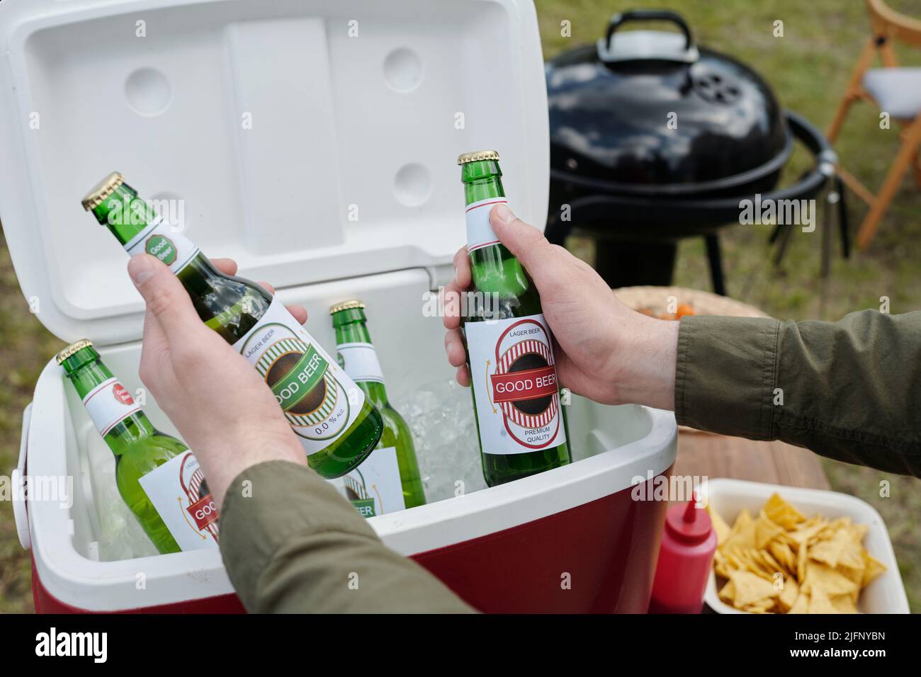 Hands of young man holding two bottles of beer over box prepared for ...