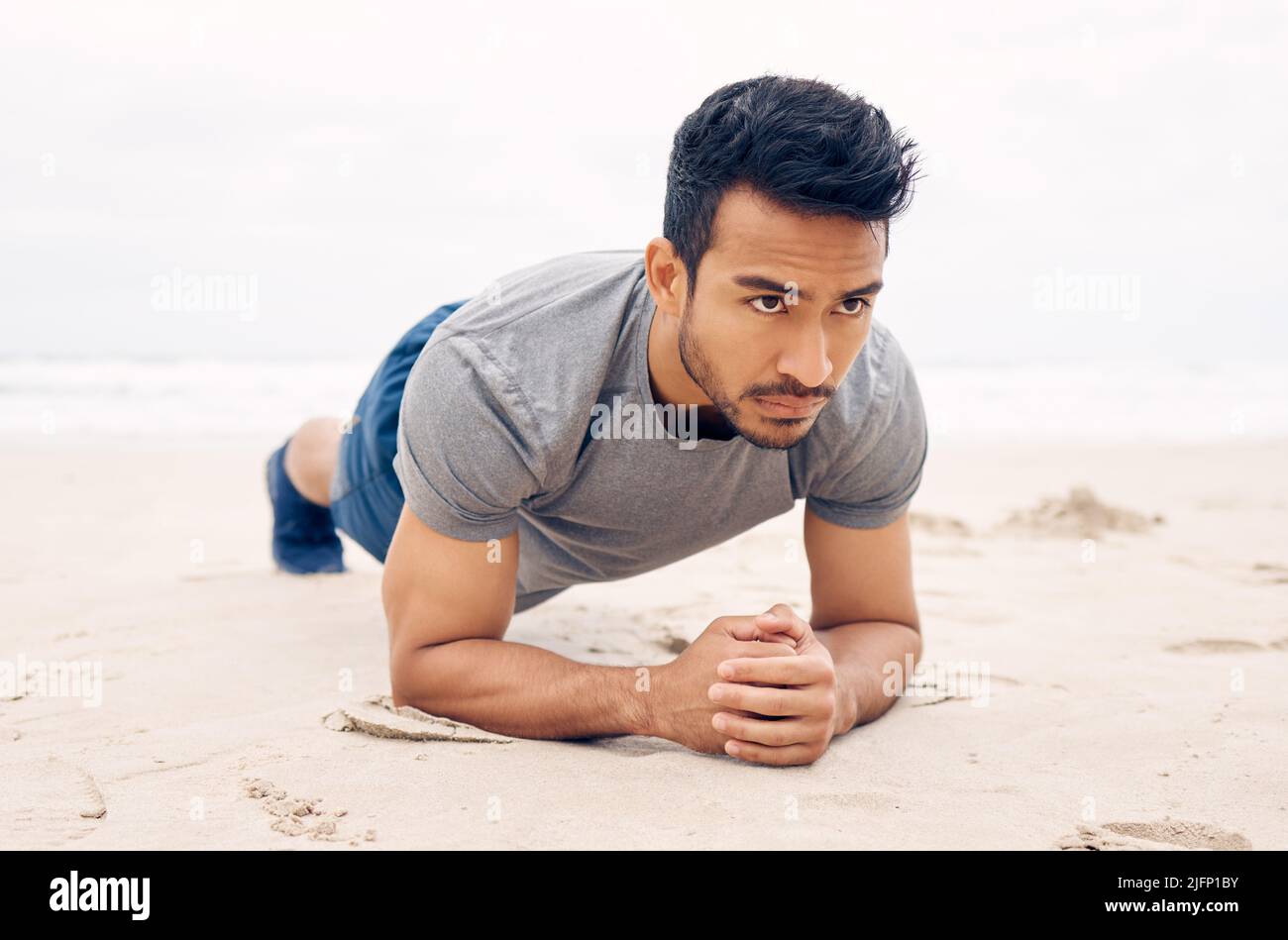 Get up and get active. Shot of a sporty young man doing plank ...