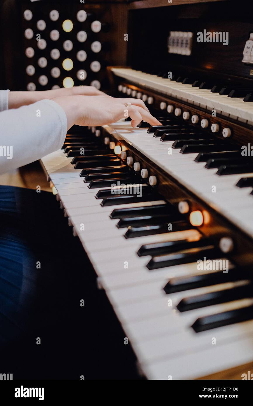 A vertical shot of a female playing a piano with multiple keyboards ...