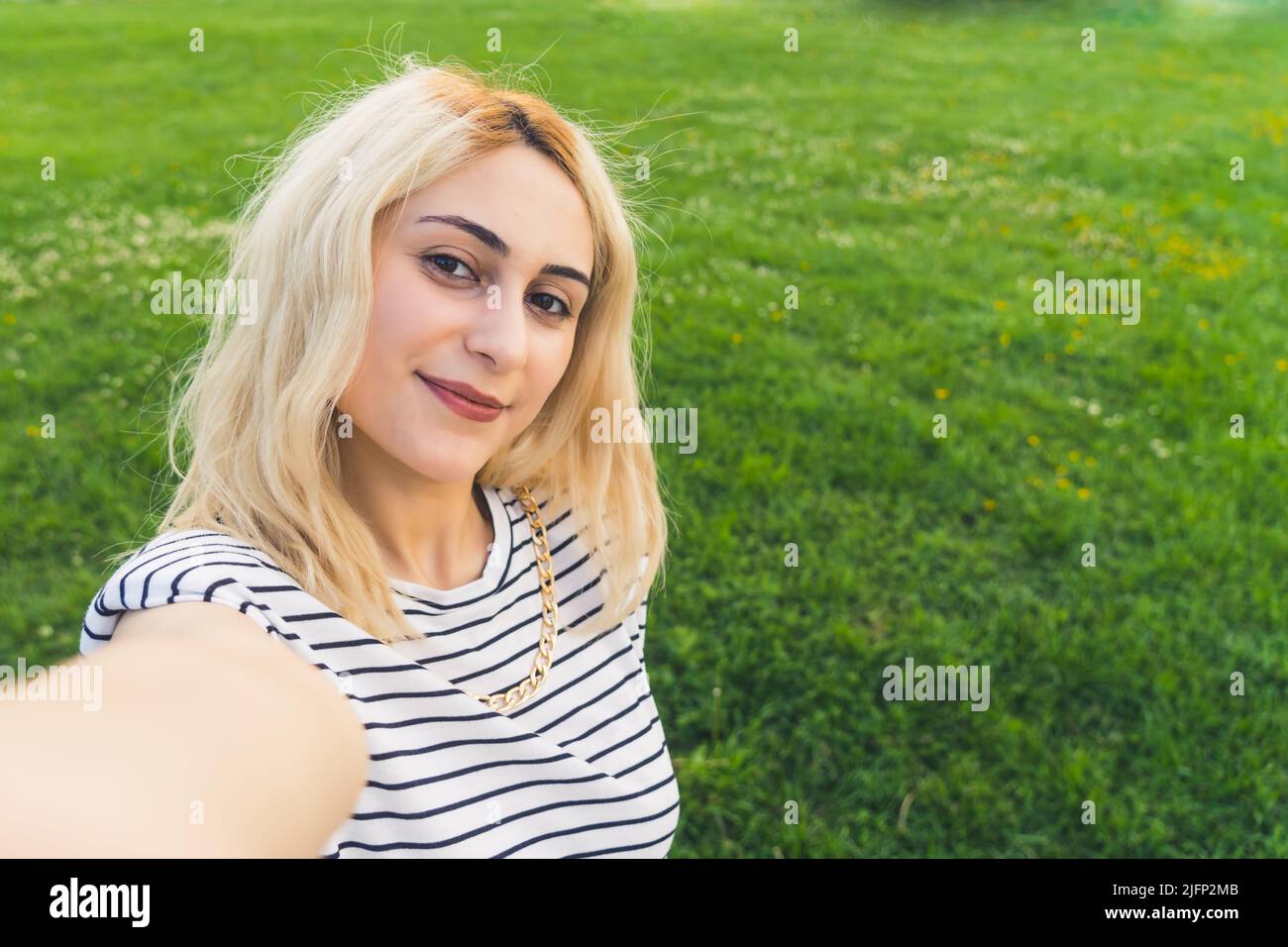selfie of a young blond girl at the park. medium closeup outdoor copy ...