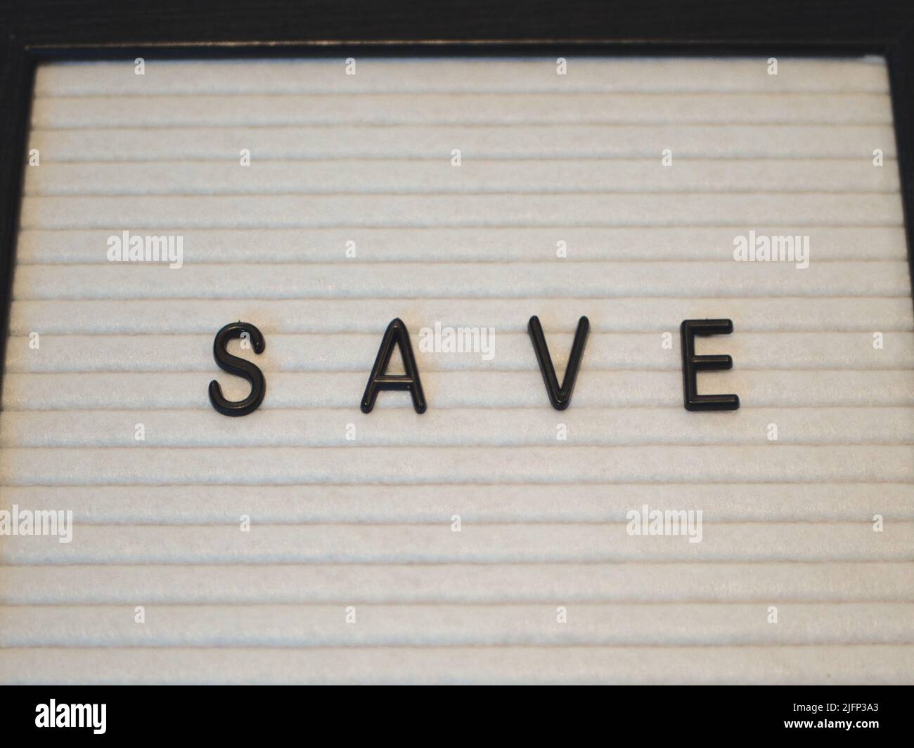 The word Save in black plastic lettering on a white and black textured ...