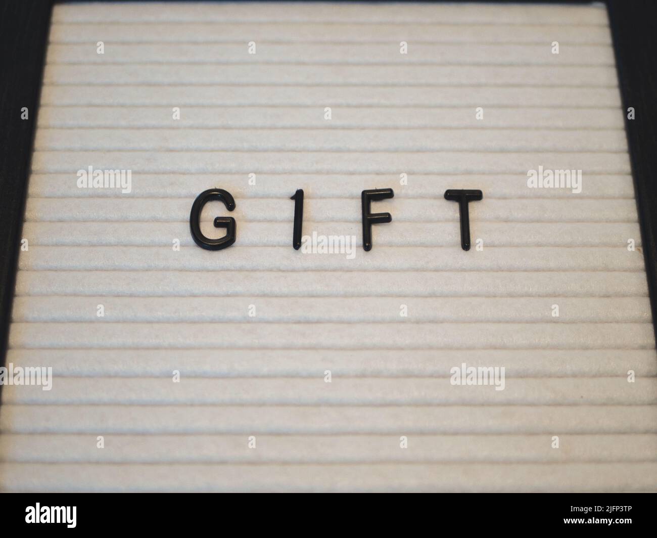The word Gift in black plastic lettering on a white and black textured ...