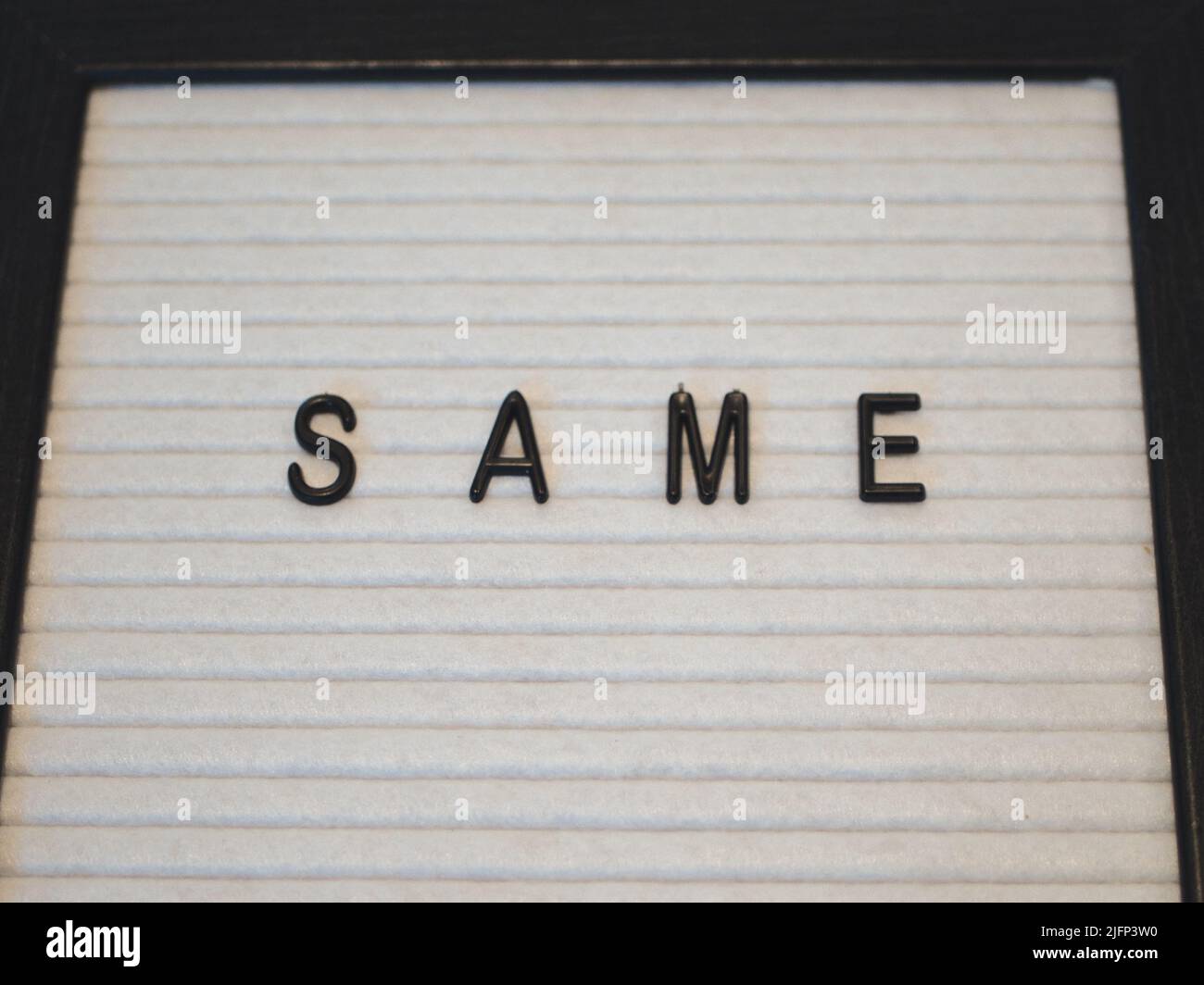 The word Same in black plastic lettering on a white and black textured ...