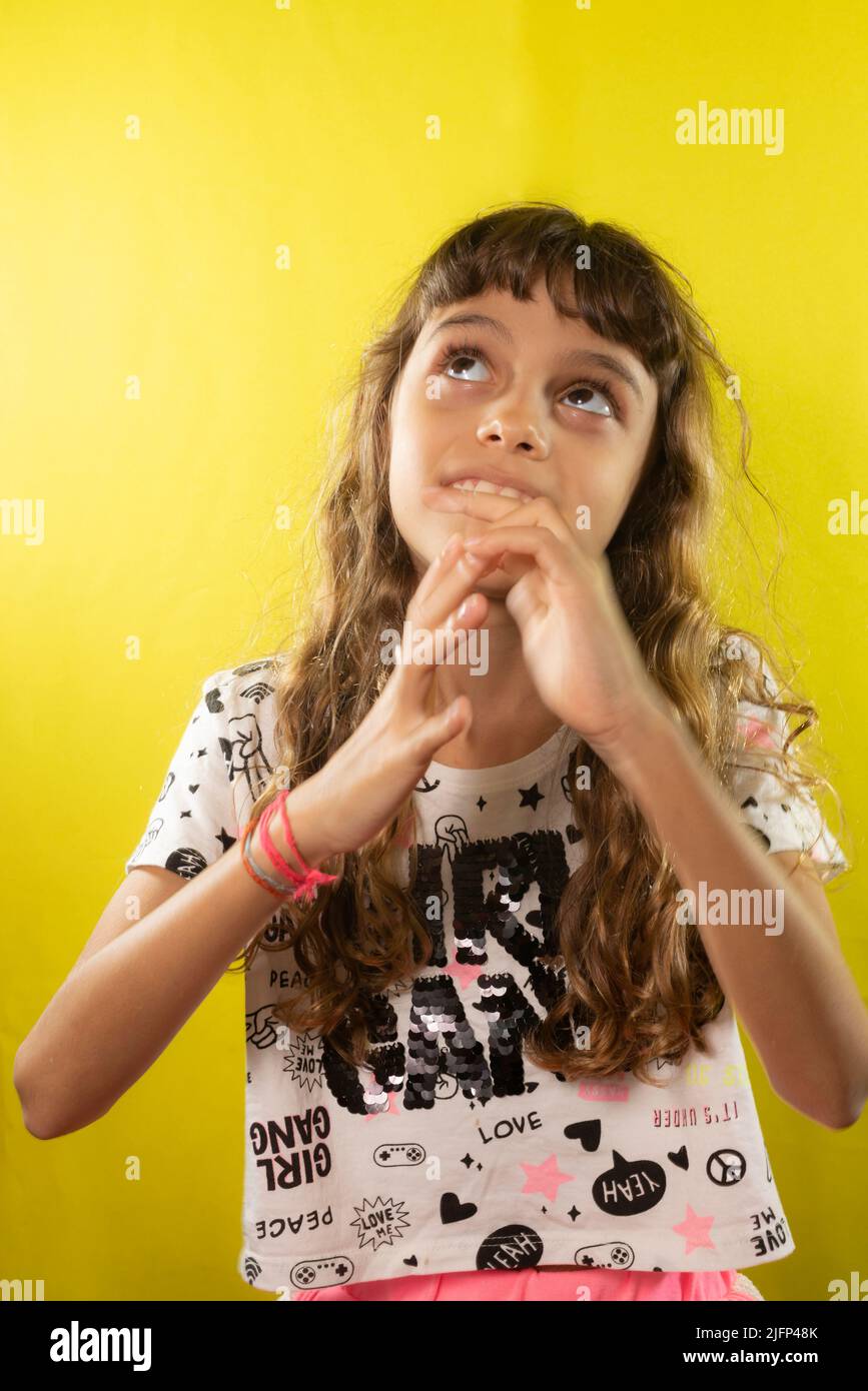 Portrait of cheerful child model sitting against yellow background in ...