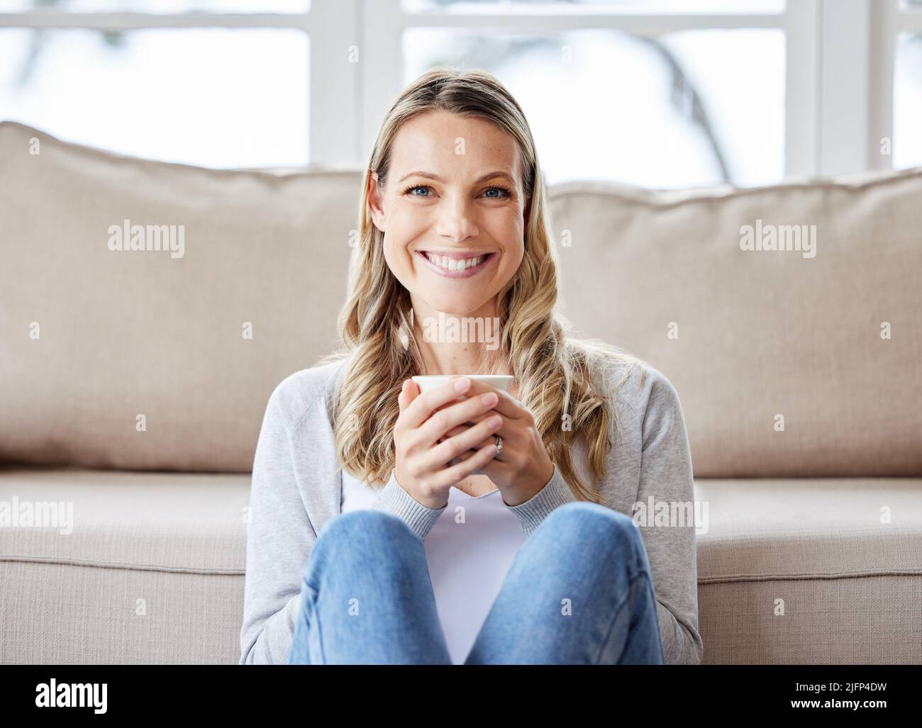 Comfy in her cosy nest. Portrait of a young woman enjoying a cup of ...