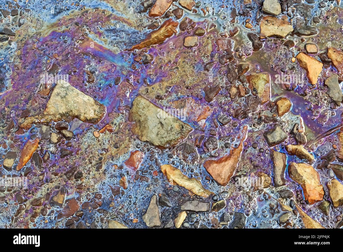 Colorful fuel and oil on an asphalt texture showing heavy enviromental ...