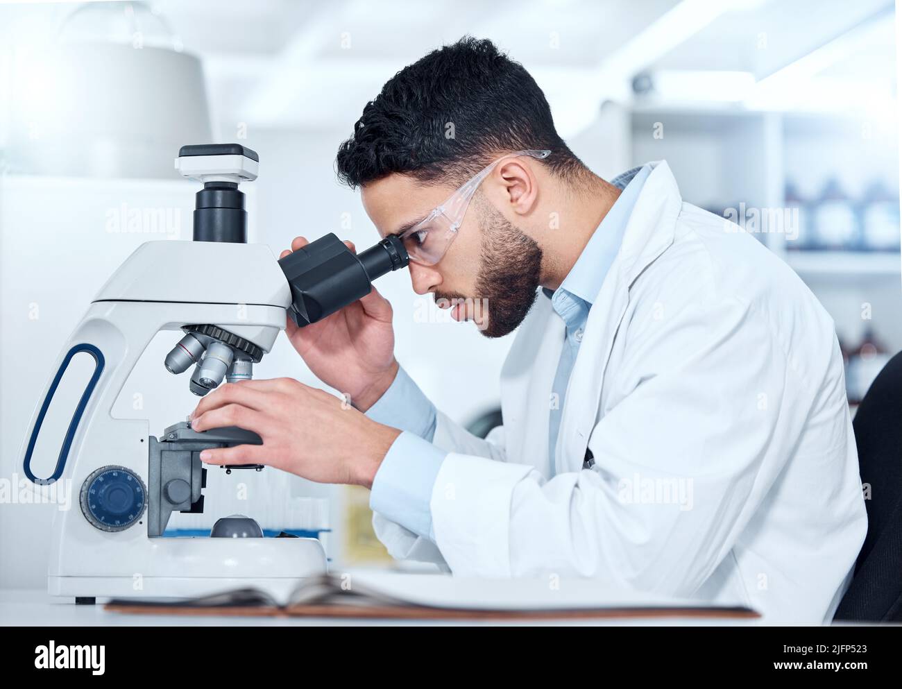 One serious young male medical scientist sitting at a desk and using a ...