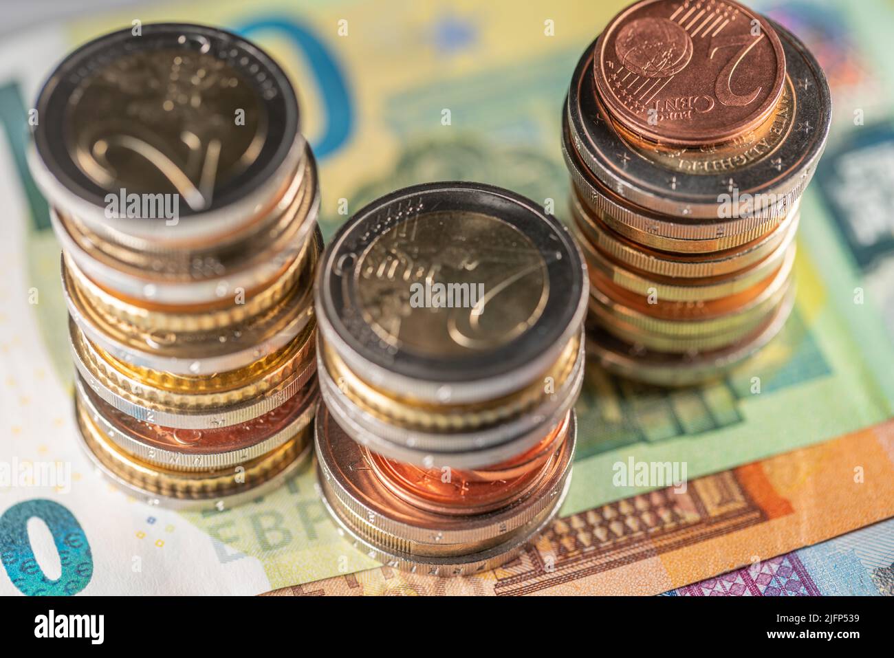 Stack of different Euro coins on Euro banknotes. Three towers of Euros ...