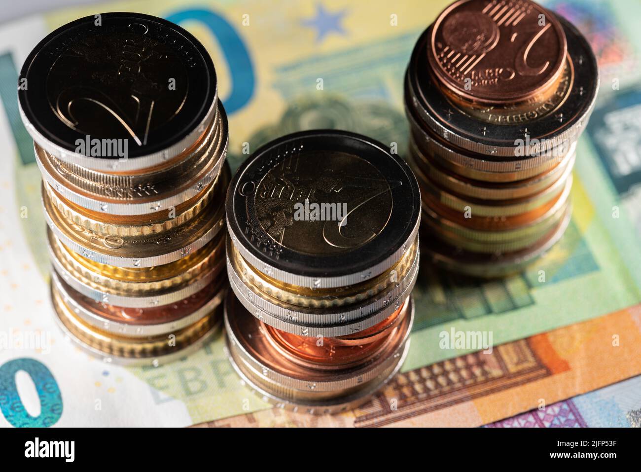 Stack of different Euro coins on Euro banknotes. Three towers of Euros ...