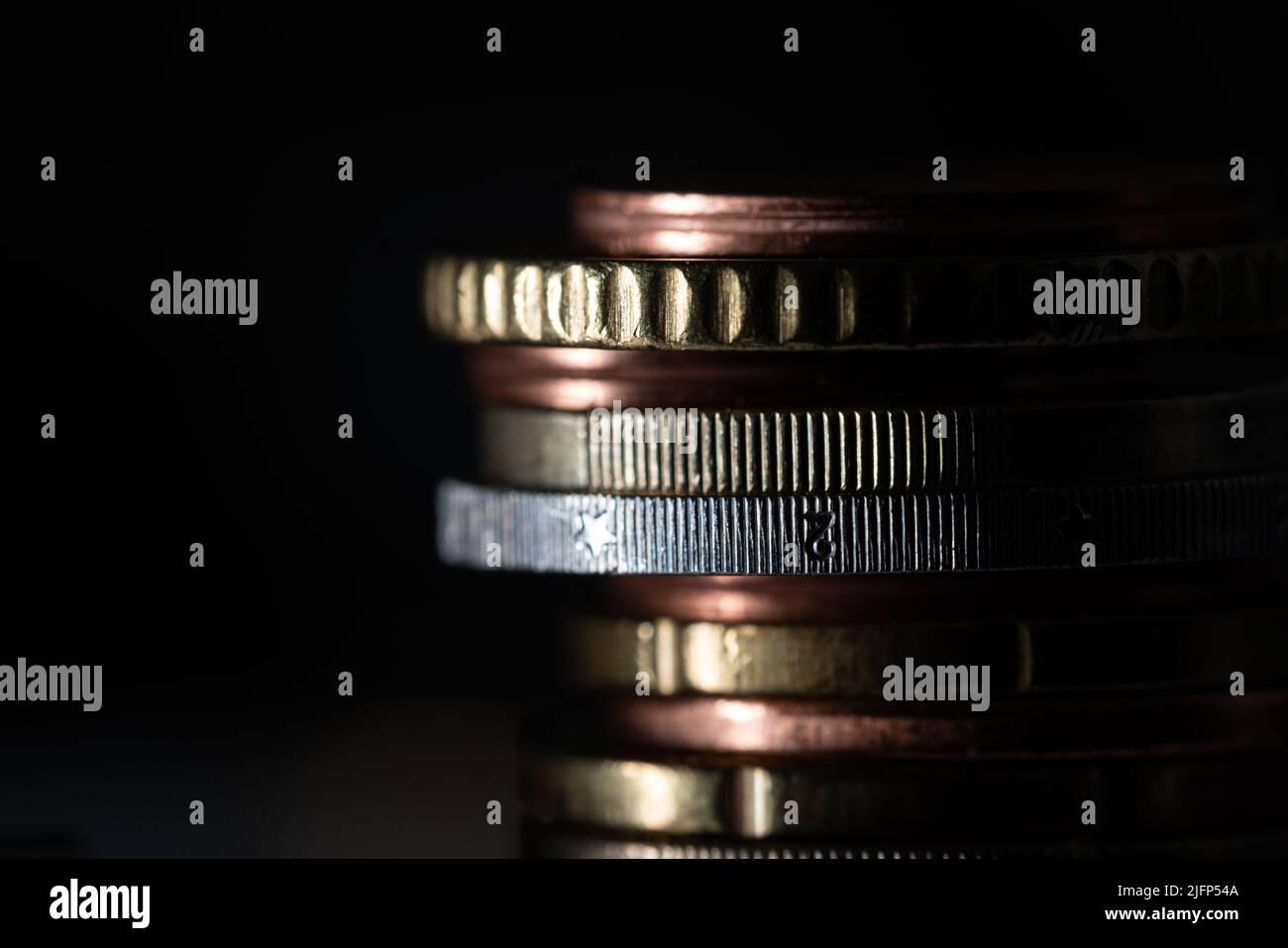 Stack of Euro coins illuminated from the side. Copper coins and golden ...