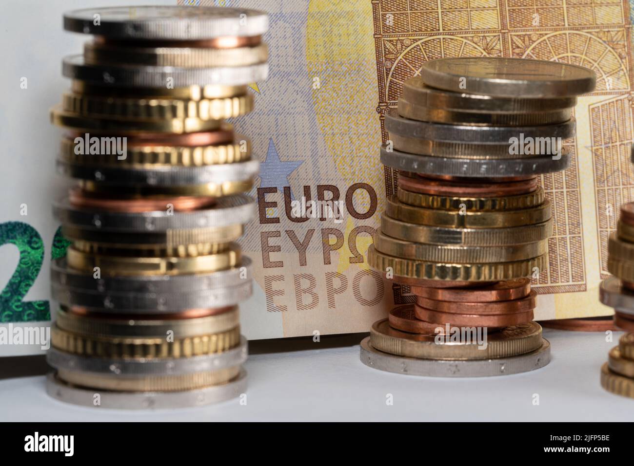 Stacked Euro coins in front of a 200 Euro banknote. EURO writing on ...