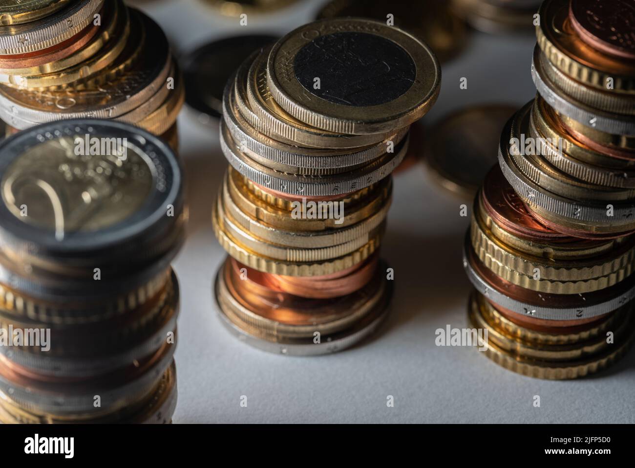 Stacked up Euro coins on white surface. One and two Euros Stock Photo ...