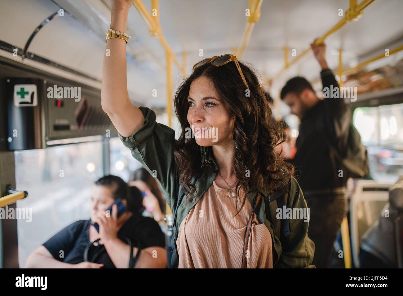 Mid adult woman commuter is standing in bus and travelling in public ...