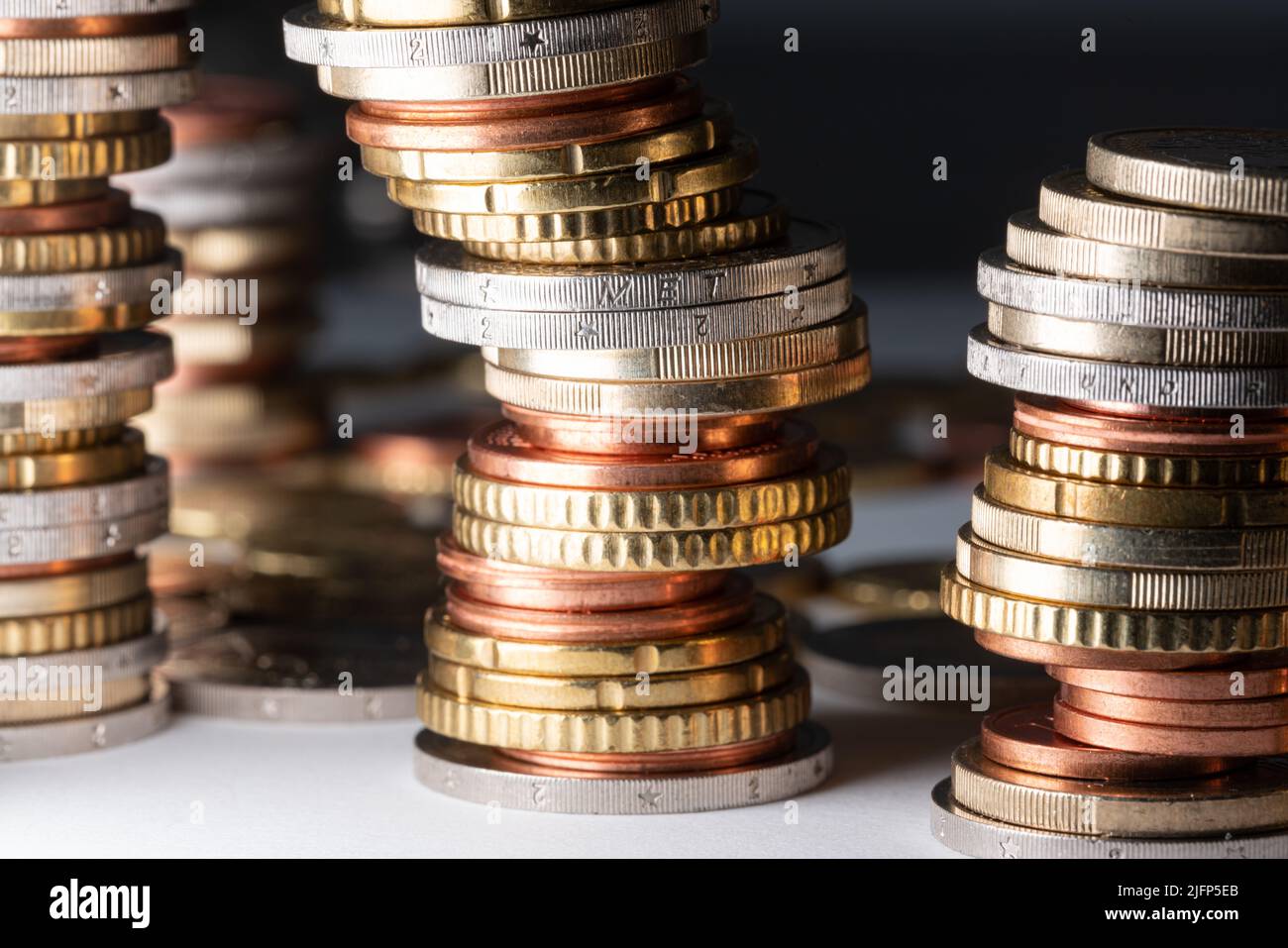 Piled up coins, Euros in different sizes leaning to the right on white ...