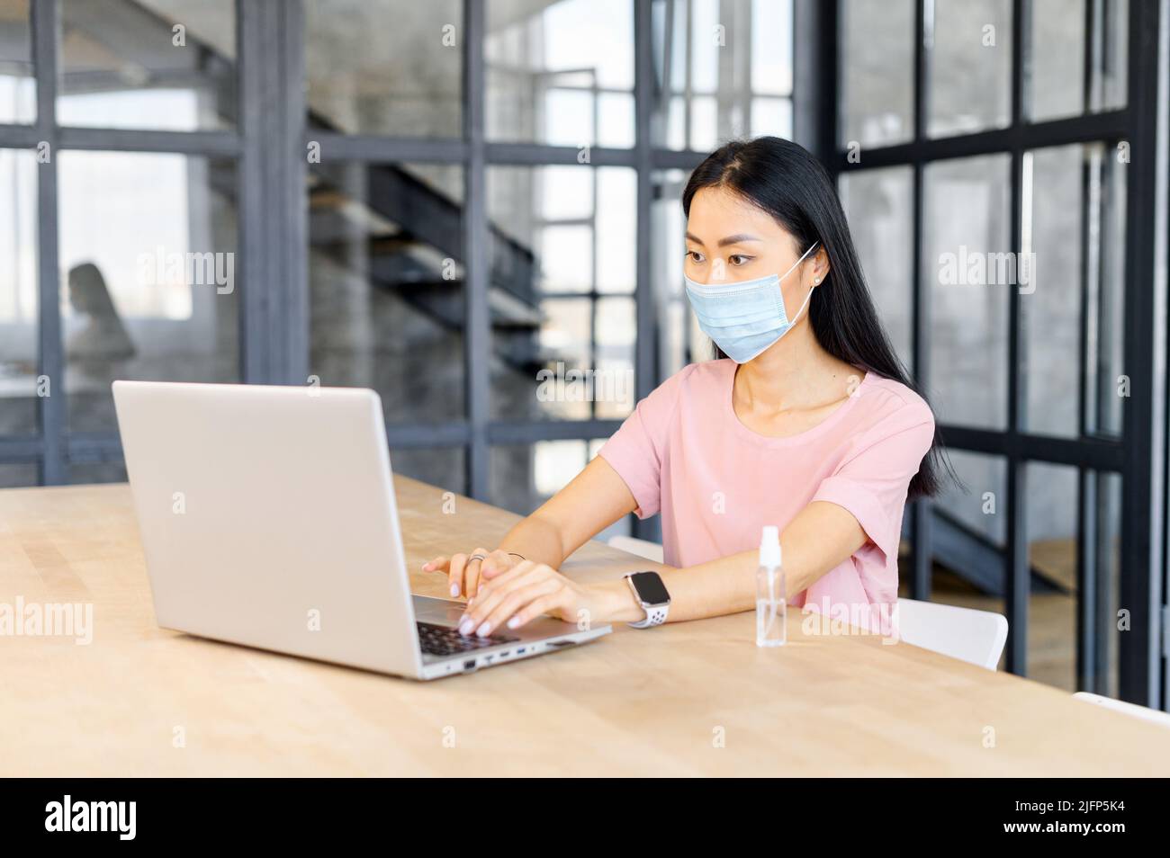 Young Asian female office worker in blue protective face mask working ...