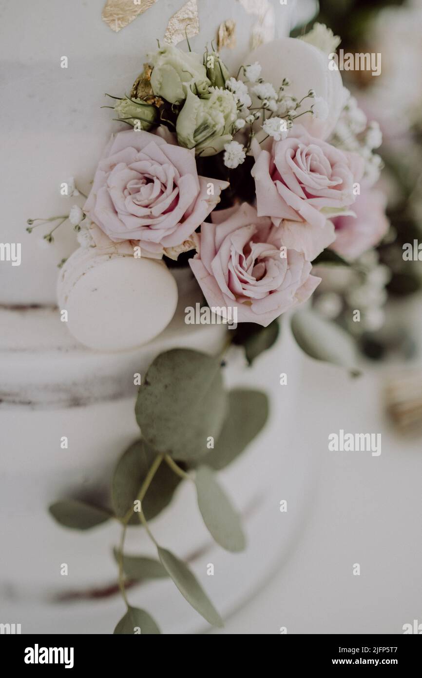 A vertical view of a white wedding cake with flowers and fancy ...
