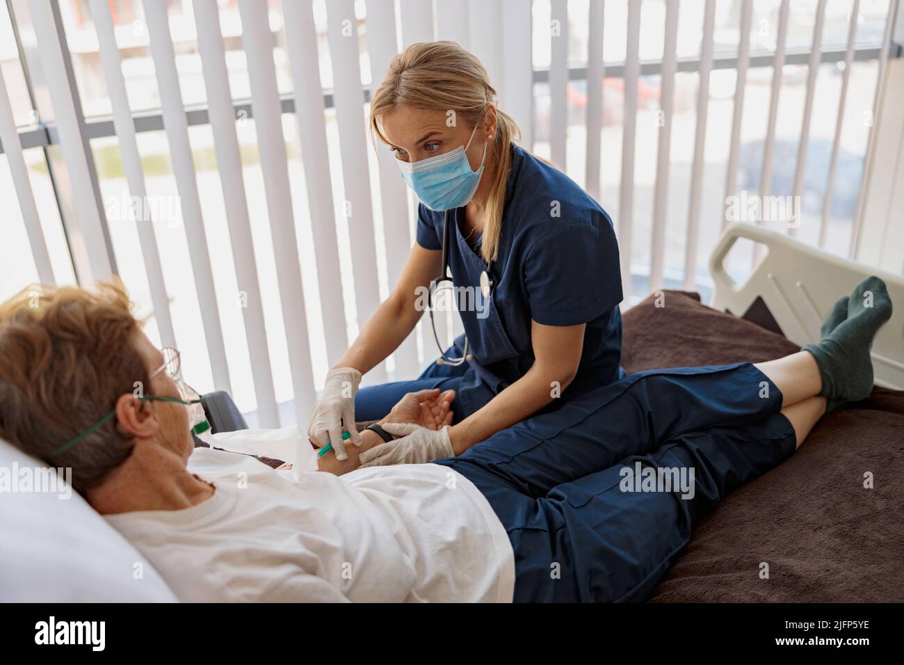 Doctor putting a drip in the arm of her patient in breathing mask ...