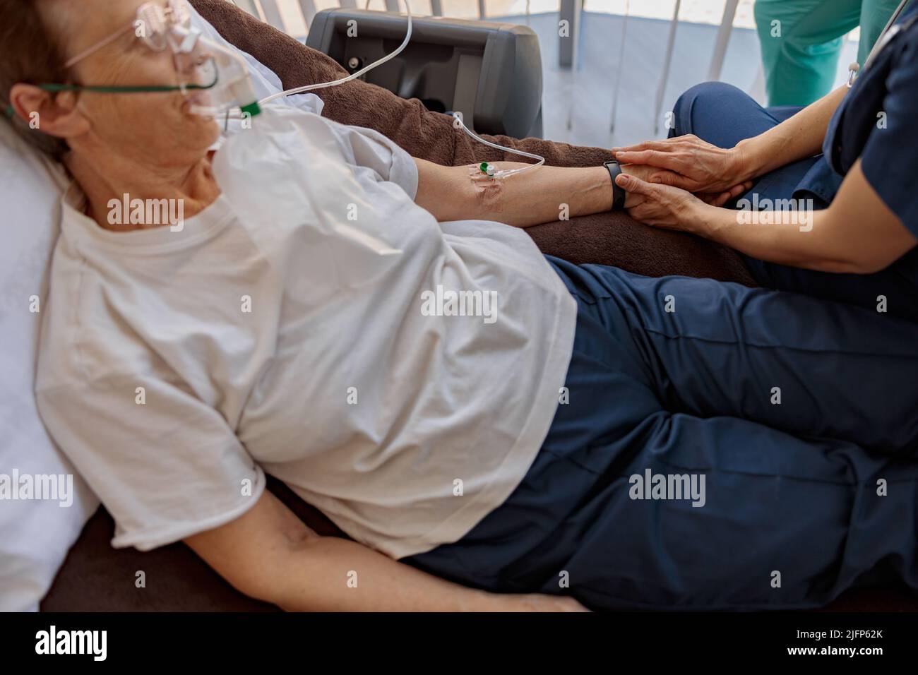 Doctor putting a drip in the arm of her patient in breathing mask ...