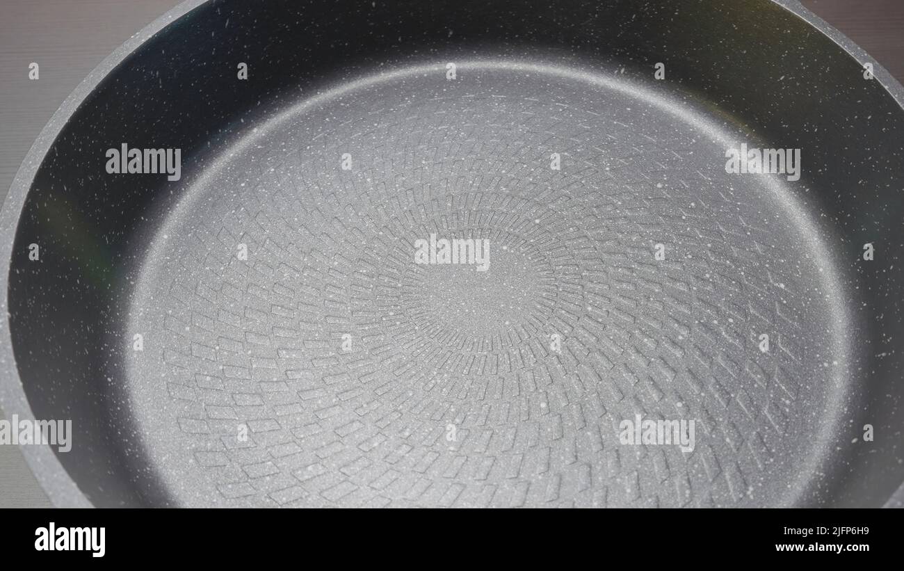 New clean frying pan. Action. Close-up of coating of modern frying pan ...